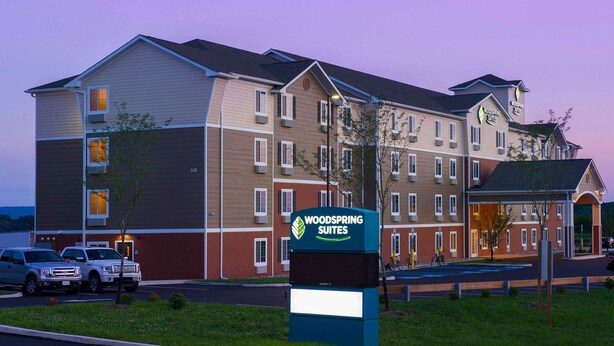 Um hotel com vários andares, com uma placa indicando "Woodspring Suites" e uma entrada coberta.
