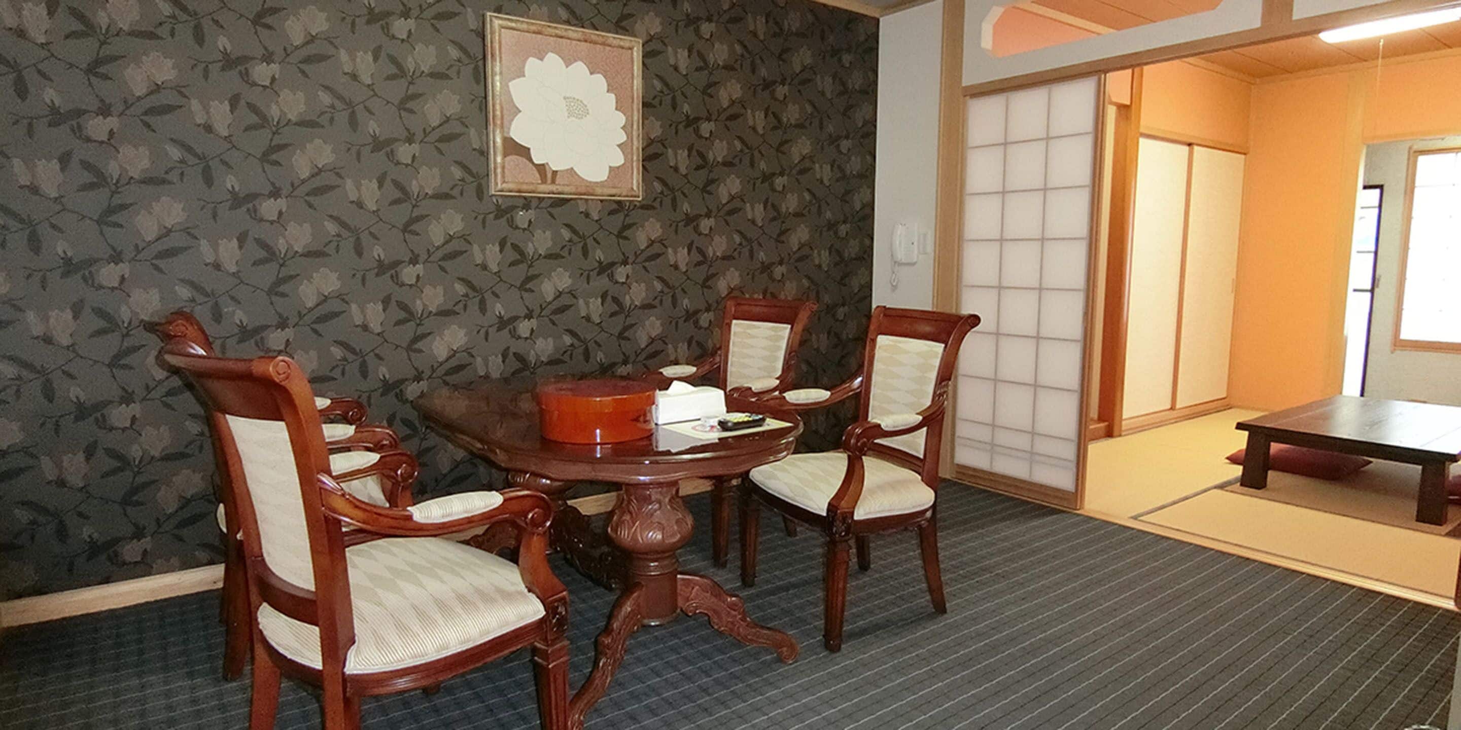 Um quarto japonês tradicional com tatames, uma mesa baixa com almofada e quatro cadeiras de madeira com almofadas.