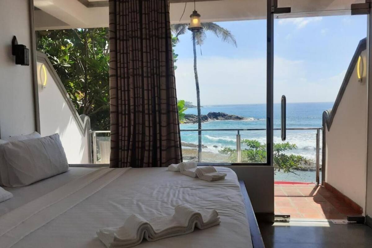 Quarto com cama, vista para o oceano e varanda.