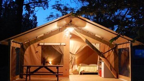 Uma tenda com uma cama, uma mesa e um pequeno armário.