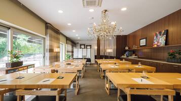 Uma sala de jantar moderna com mesas e cadeiras de madeira e um lustre.