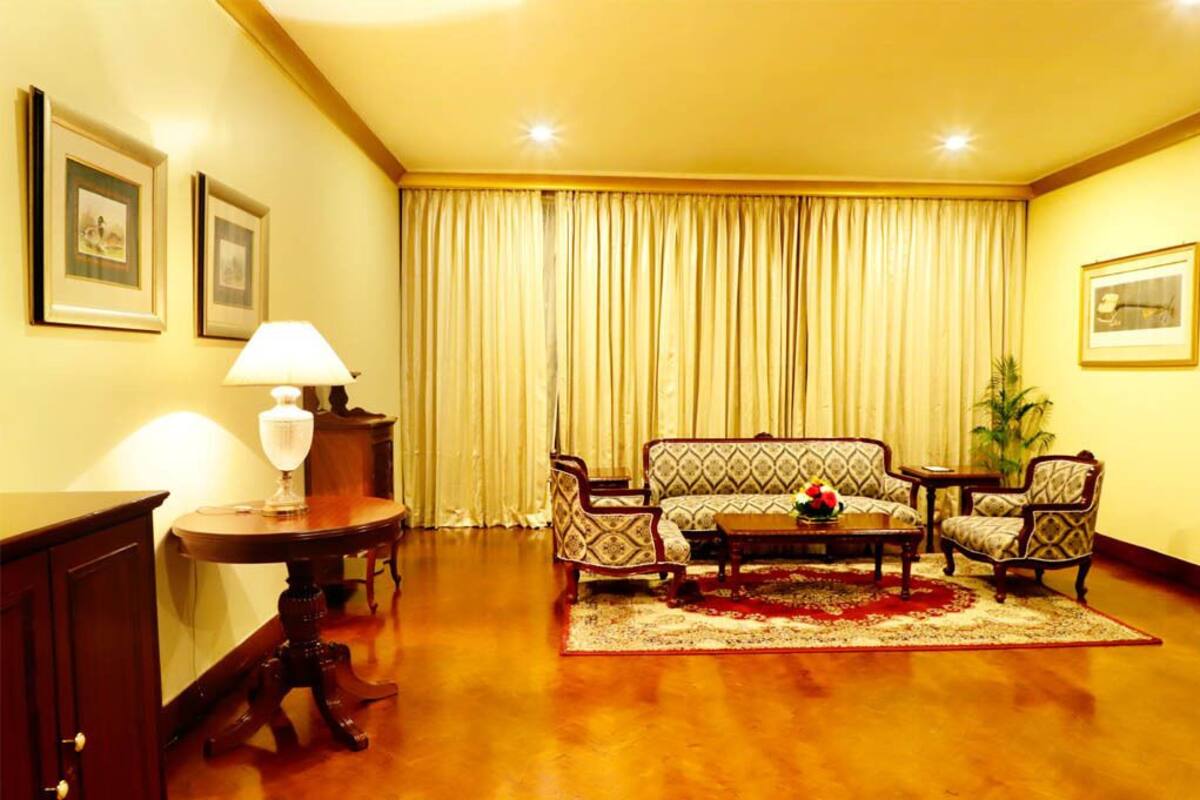 Uma sala de estar com sofá, mesa de centro, luminária e mesa lateral.