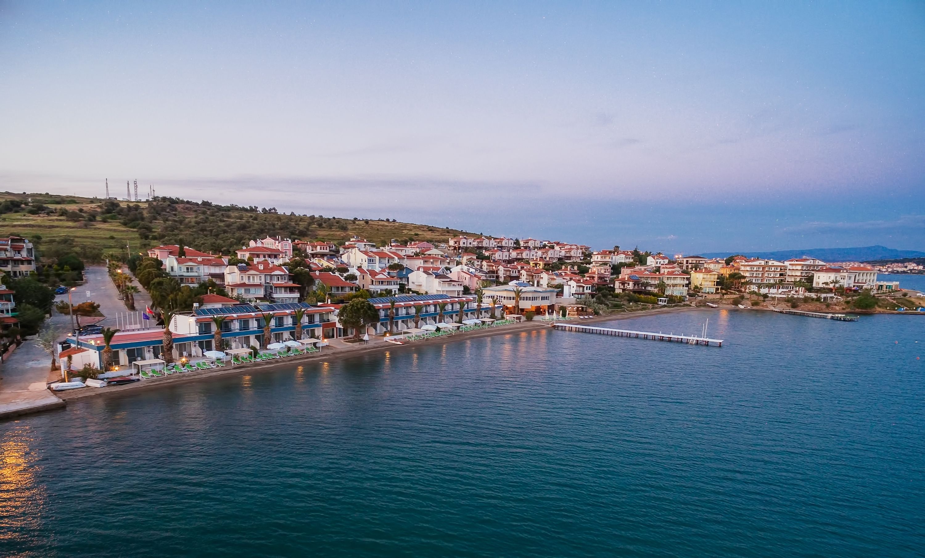 Uma vila costeira com um porto de iates, edifícios à beira-mar e um cais.