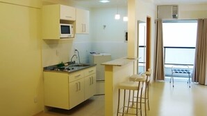 Uma cozinha compacta com micro-ondas, pia e banquetas.