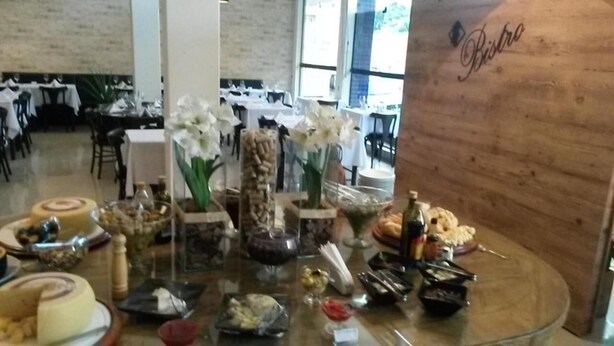 Disposição de buffet com diversos pratos e bebidas sobre uma mesa de vidro.