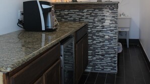 Uma cozinha compacta com cafeteira, painel de azulejos e iluminação pendente.