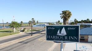 Placa do Harbour Inn em Rockport, Texas, com vista clara da área ao redor, incluindo estrada, palmeiras e um corpo de água.