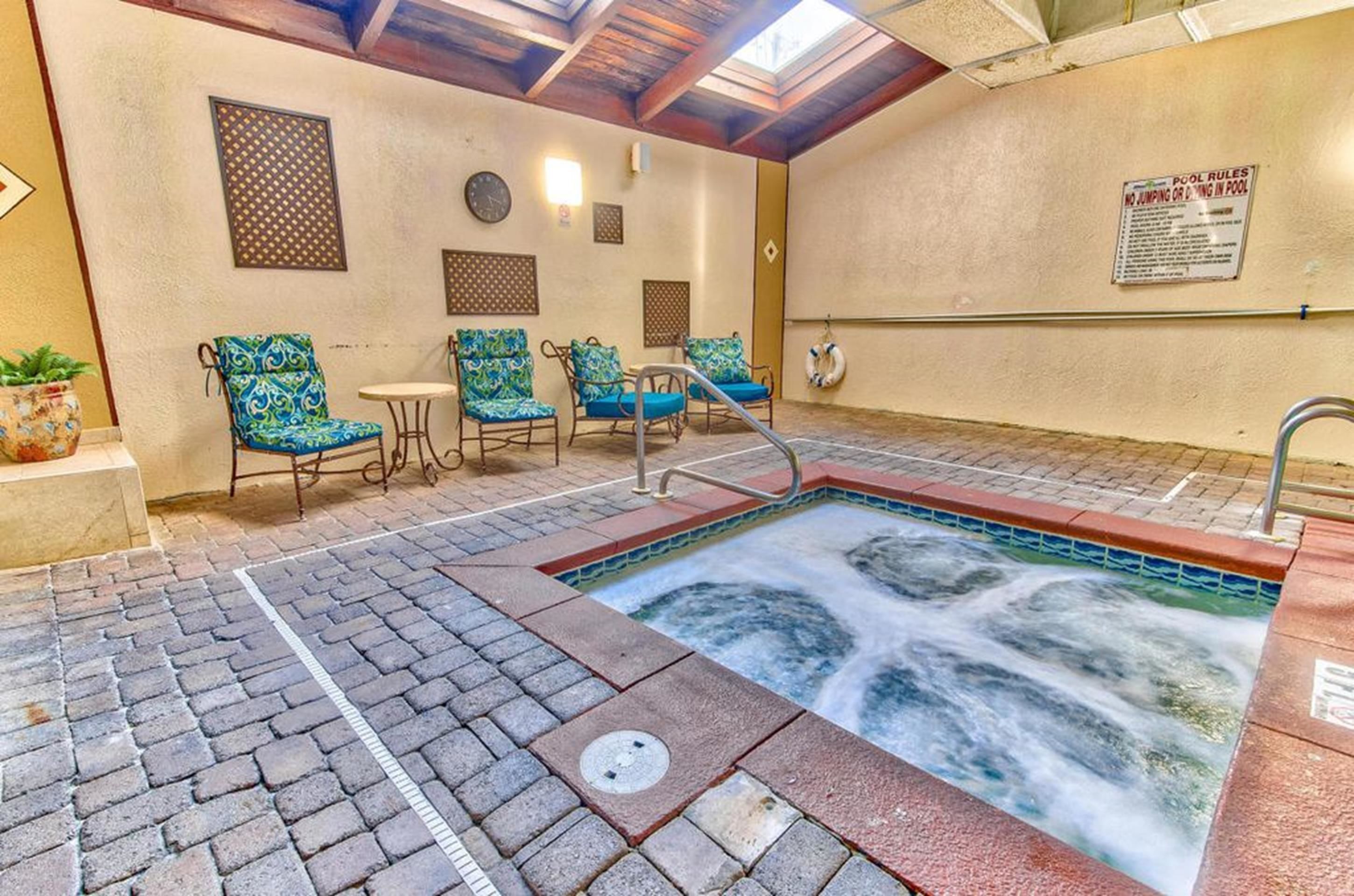 Uma área de spa com hidromassagem, espreguiçadeiras e um aviso sobre as regras da piscina.