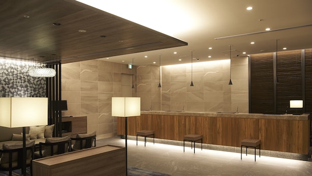 Um lobby moderno com balcão de recepção, área de estar e um grande candelabro.