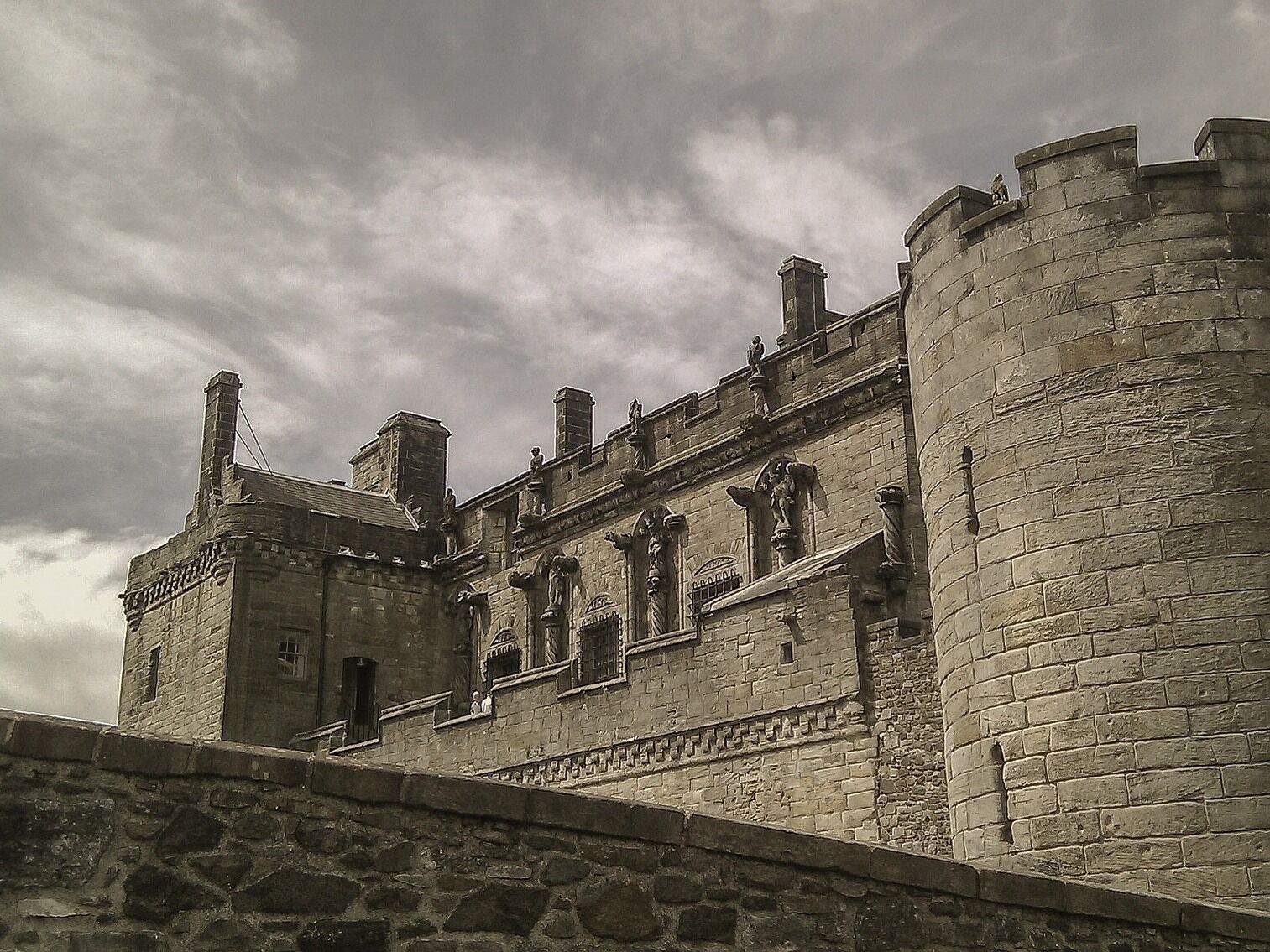 Um edifício histórico de pedra com várias janelas e uma torre imponente.