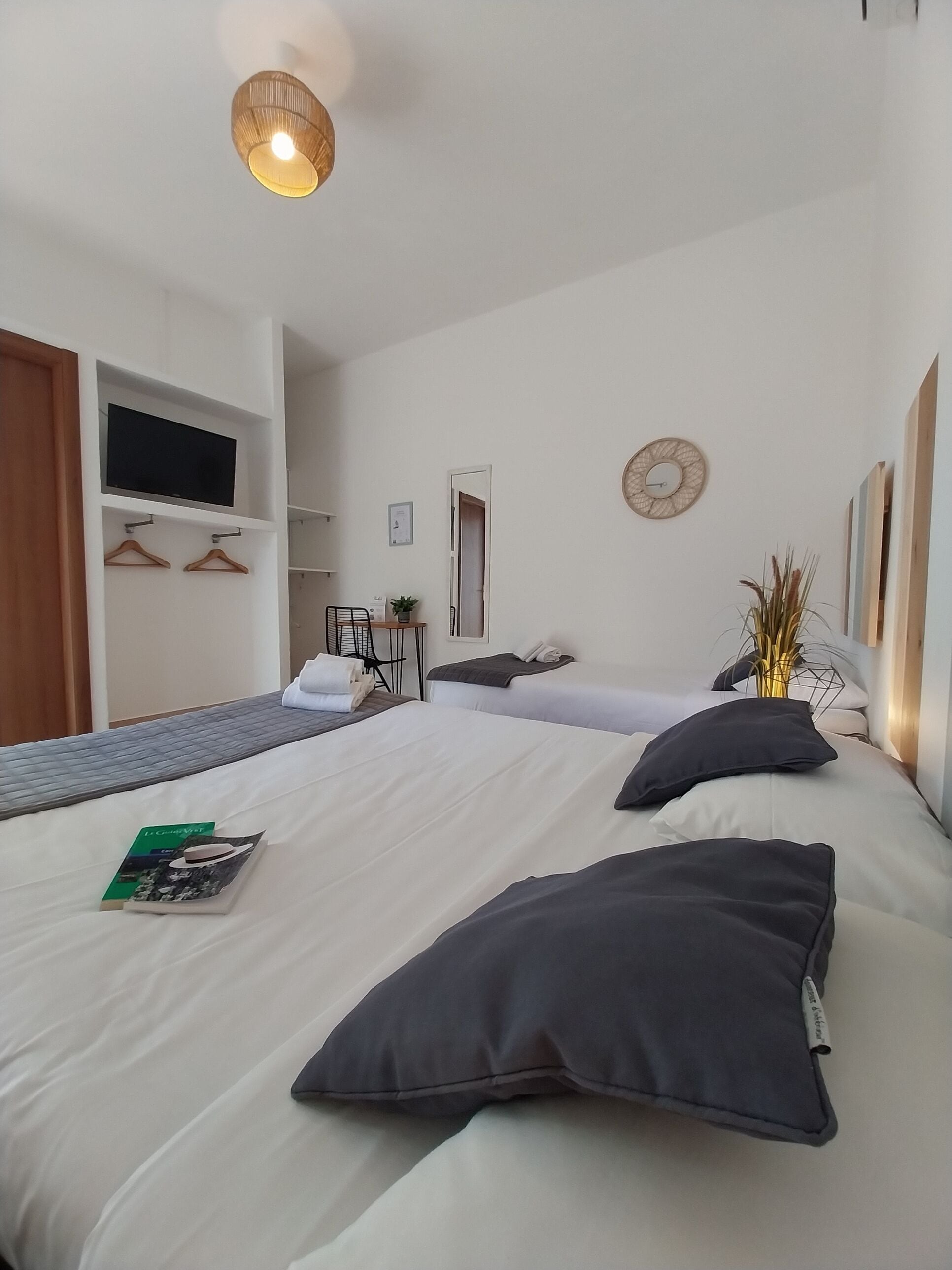 Quarto de hotel moderno com uma cama grande, uma escrivaninha, uma cadeira, uma televisão e um elemento decorativo na parede.
