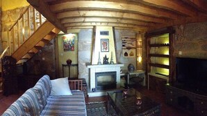 Uma sala de estar aconchegante com lareira, televisão e escada que leva a um andar superior.