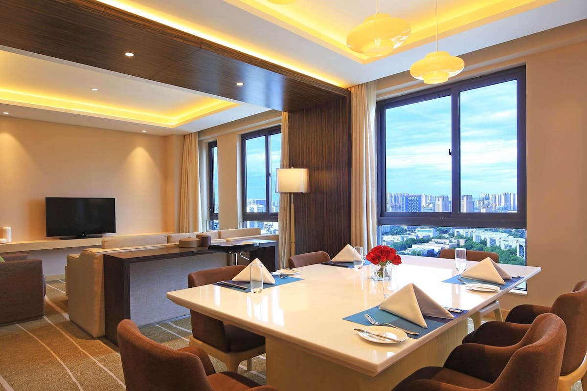 Quarto de hotel com área de refeições, televisão e vista para a cidade.