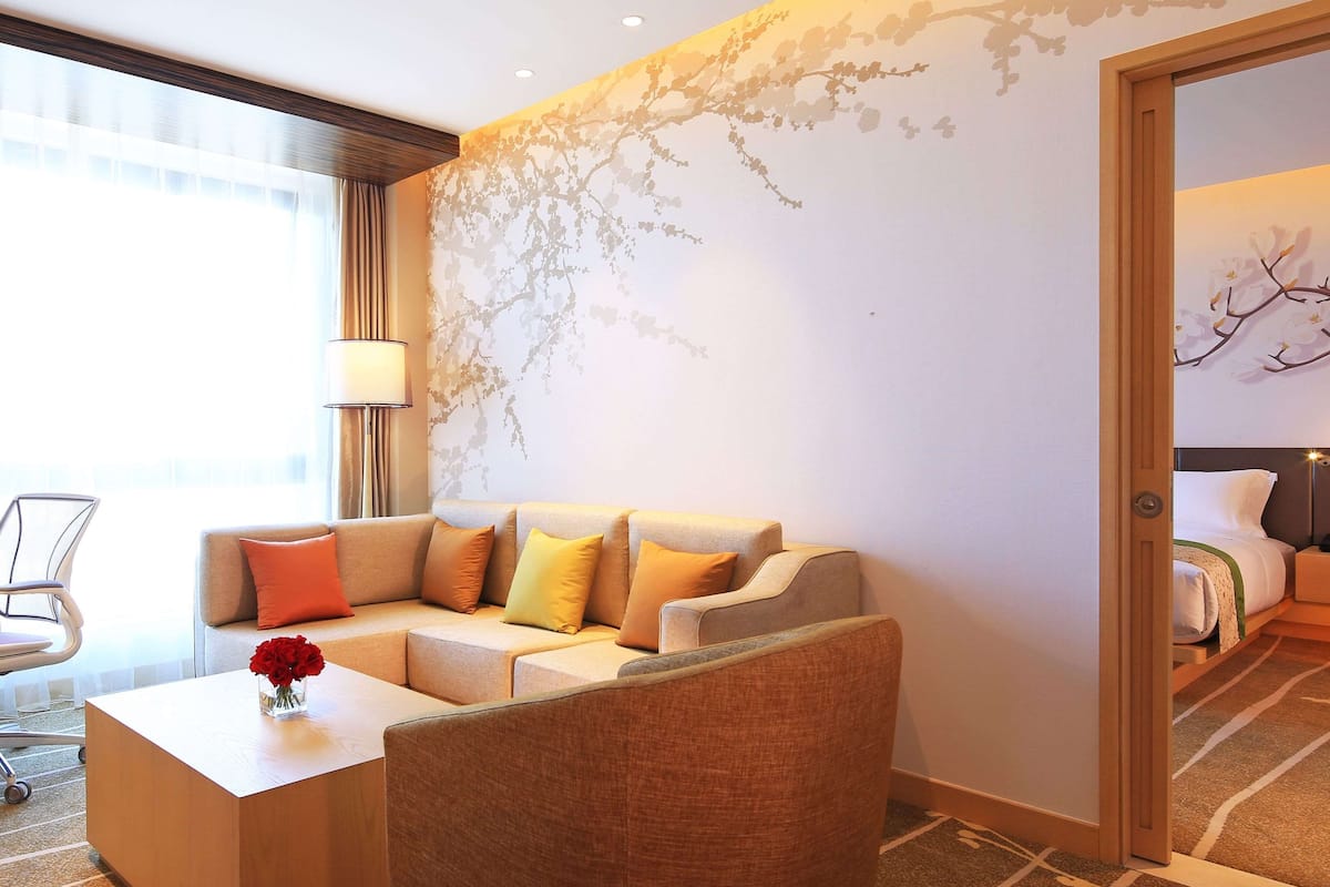 Quarto de hotel moderno com sofá, mesa de centro e luminária.