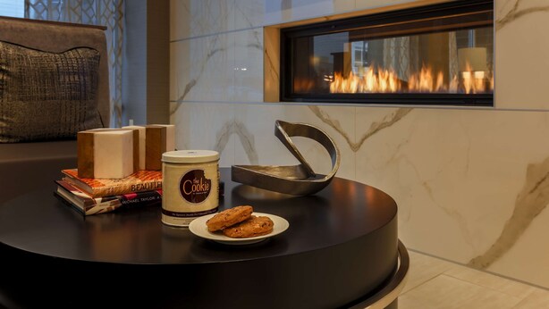 Uma sala de estar moderna com lareira, uma mesa de centro com livros, um pote de biscoitos e um prato de biscoitos.
