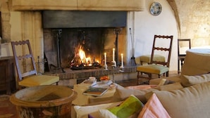 Uma sala de estar aconchegante com lareira, assentos confortáveis e teto de pedra rústica.