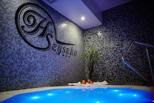 Uma área de spa com parede em mosaico, banheira de hidromassagem e escadaria.