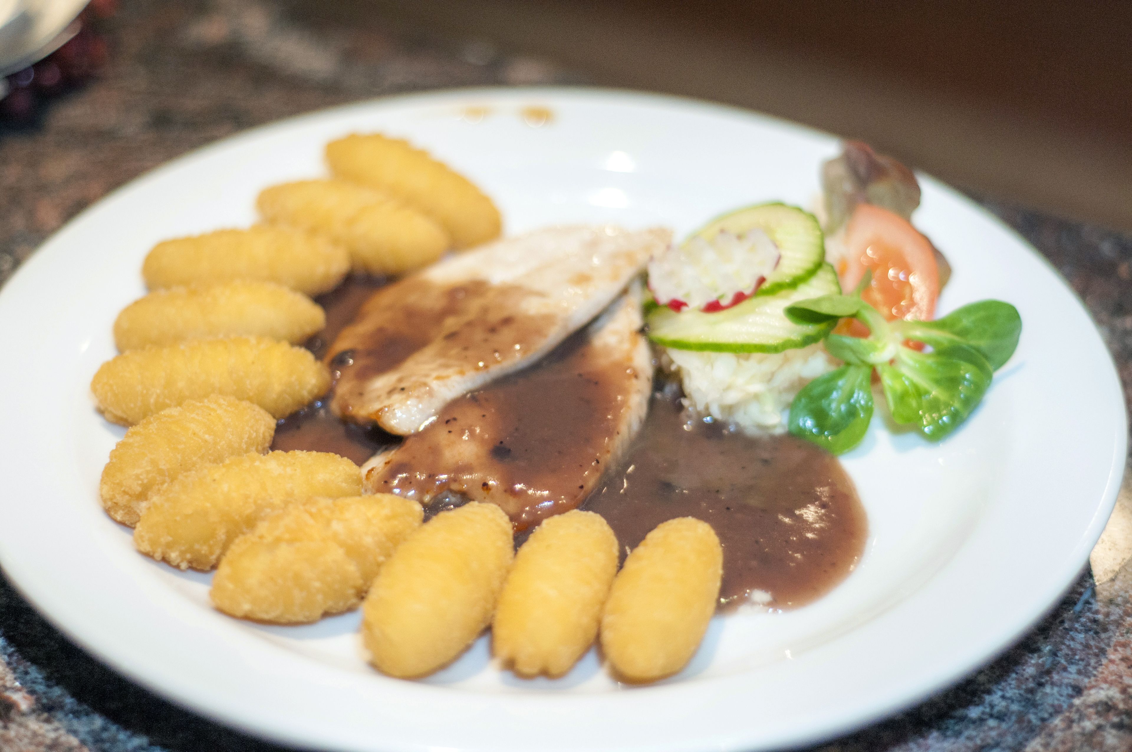 Um prato com carne, molho e legumes.