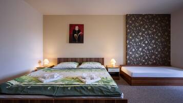 Uma cama bem arrumada com colcha floral verde e branca, duas luminárias de cabeceira, uma mesa de cabeceira, um quadro de flor pendurado na parede e papel de parede com padrão floral na parede adjacente.