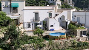 Área residencial com edifícios brancos, uma piscina e montanhas ao fundo.