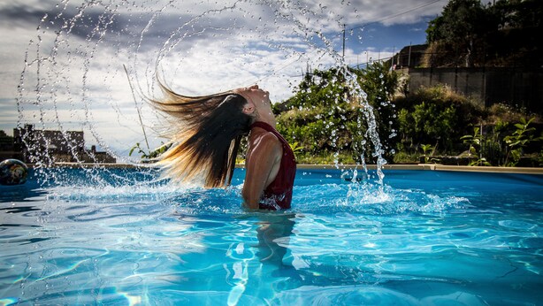 Uma pessoa em uma piscina, com água espirrando ao redor.