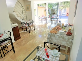 Uma sala de jantar com uma mesa comprida posta para refeição, cadeiras e uma escada que leva a outro andar.