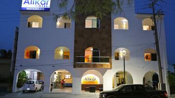 Um hotel com uma placa que diz "Alikar Hotel Restaurante" e várias entradas em arco.