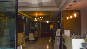 Um saguão de hotel com balcão de check-in, área de estar e escadas.