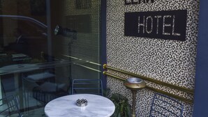 Uma área de estar externa com uma mesa redonda e duas cadeiras, um vaso de planta e uma parede com o texto "ELAN HOTEL".