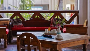 Uma área de refeições com mesa de madeira, cadeiras e um banco estofado vermelho.