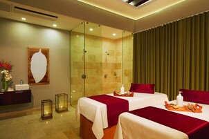Quarto de hotel com duas camas, box de vidro para o chuveiro, toucador com espelho e uma mesinha com bandeja.