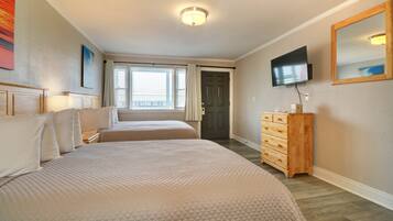 Quarto de hotel com duas camas, uma cômoda, uma televisão e uma porta.