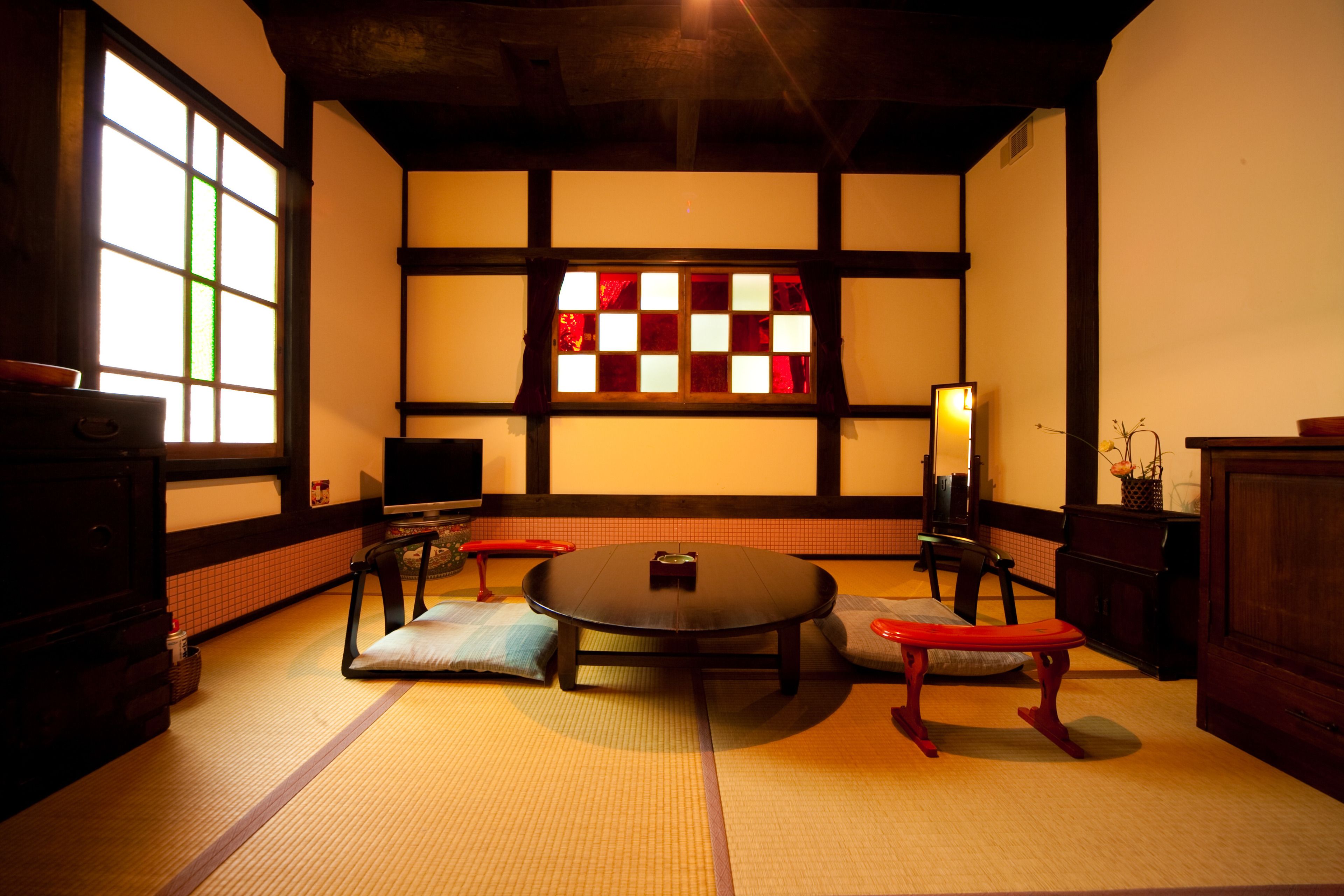 Um quarto japonês tradicional, com tatames, uma mesa baixa e uma porta corrediça com padrão xadrez.