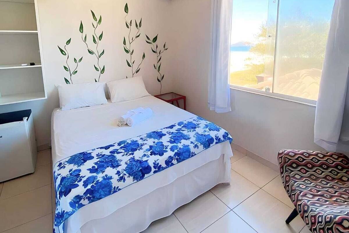 Quarto com cama, janela, cadeira e prateleira.