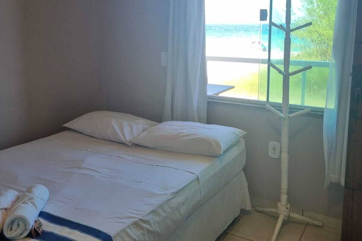 Um quarto com cama, janela vista para o mar e uma árvore de estimação.