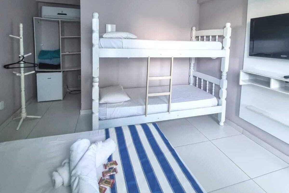 Quarto com beliche, televisão, guarda-roupa e tapete listrado.