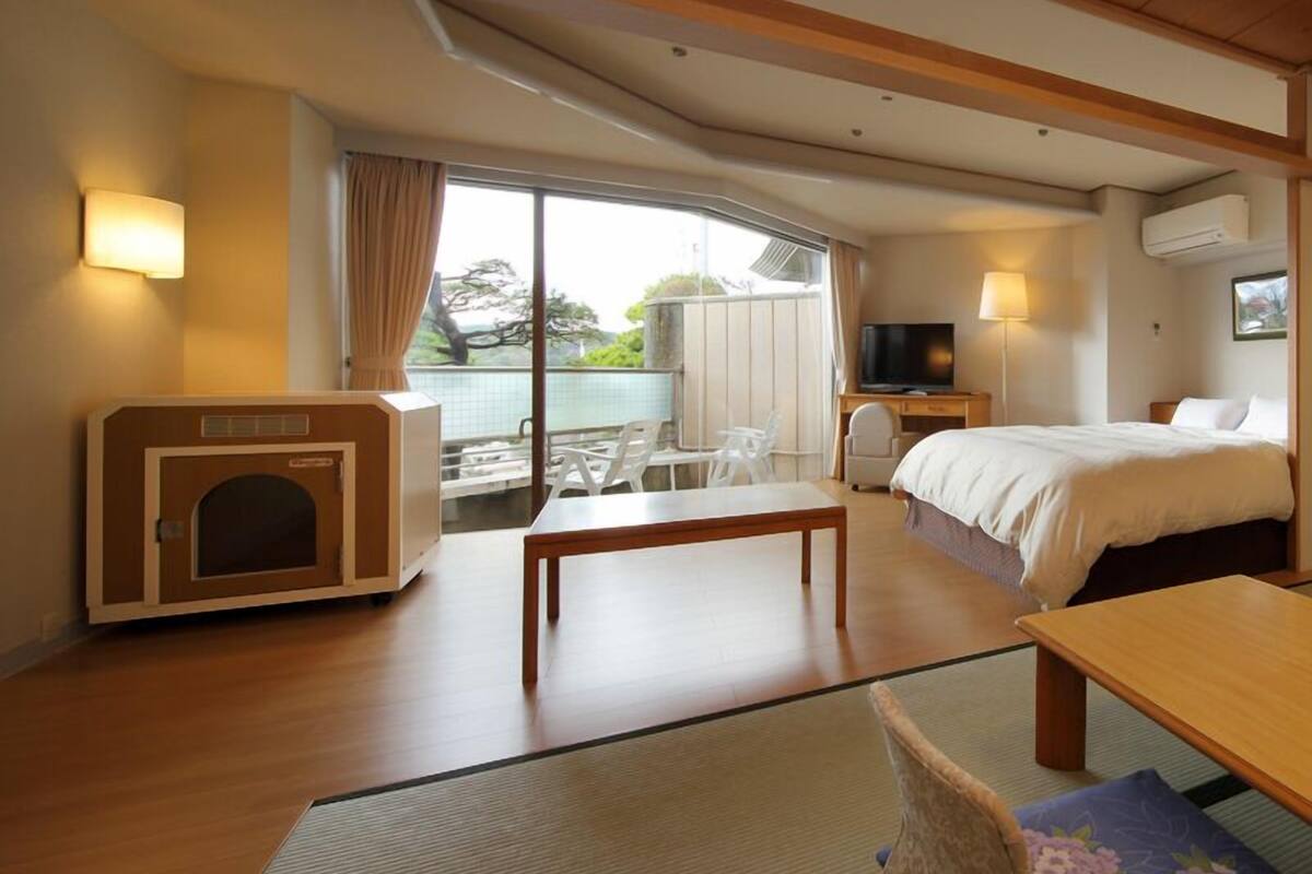 Quarto de hotel com cama, televisão, lareira, mesa de jantar e vista para o exterior.