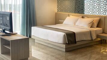 Quarto de hotel moderno com uma cama grande, uma escrivaninha com computador e uma parede estampada.