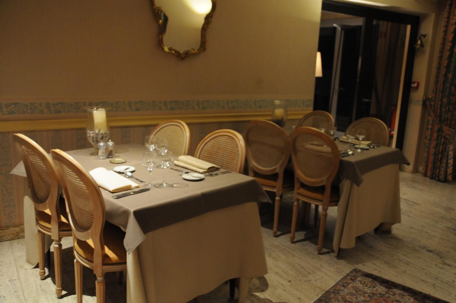 Uma sala de jantar com mesa posta para seis pessoas, incluindo cadeiras, pratos, copos e uma vela.