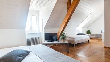 Quarto moderno estilo loft com teto inclinado, uma janela grande, cama, escrivaninha e planta em vaso.