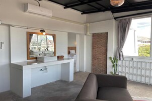 Casa de banho moderna com toucador branco, espelho grande e parede de tijolos integrada.