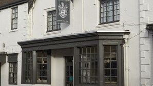 Um edifício tradicional com uma placa bem visível com a inscrição "Crowdey Arms Hotel". Apresenta um estilo arquitetônico clássico, com telhado íngreme e várias janelas.