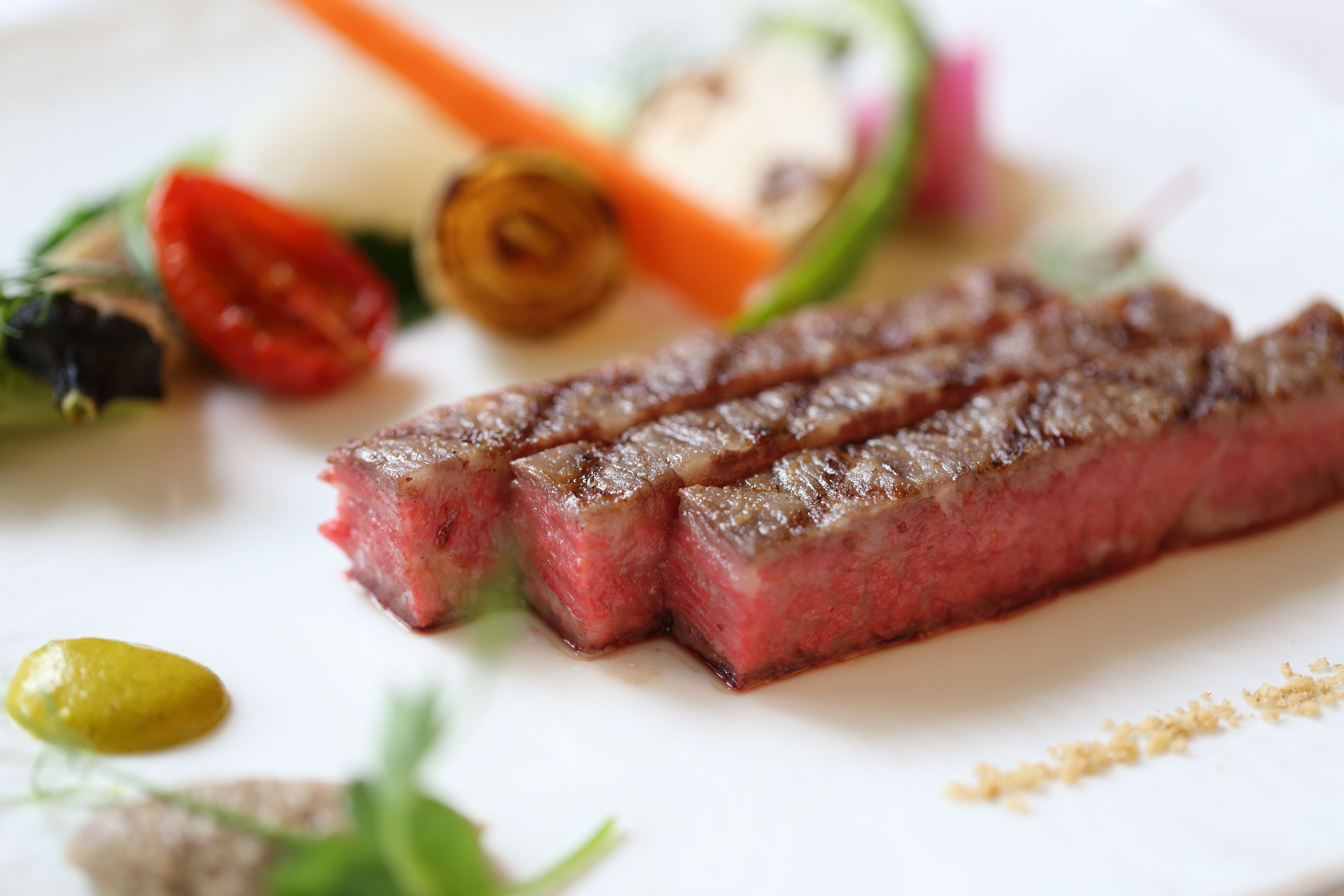 Prato com bife, legumes e uma azeitona.
