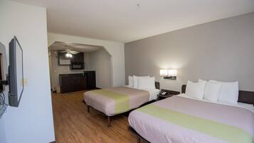 Quarto de hotel com duas camas, cozinha compacta e televisão.