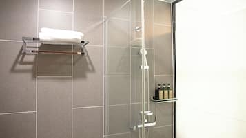 Uma área de chuveiro moderna com porta de vidro, um porta-toalhas e um prateleira com produtos de higiene pessoal.