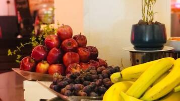 Exposição de frutas com maçãs, uvas e bananas sobre uma mesa de madeira.