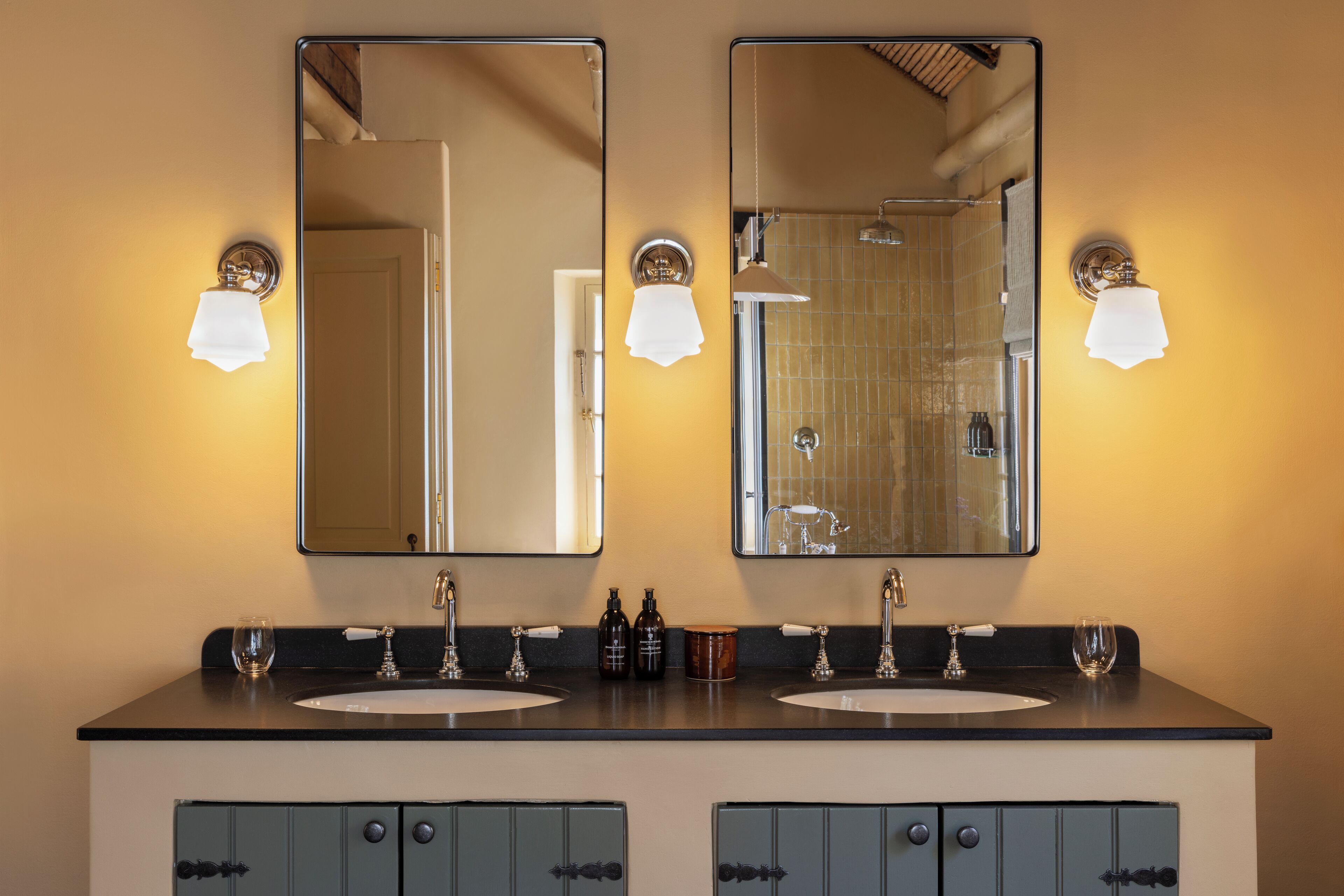 Casa de banho com duas pias, dois espelhos e duas luminárias fixadas na parede.