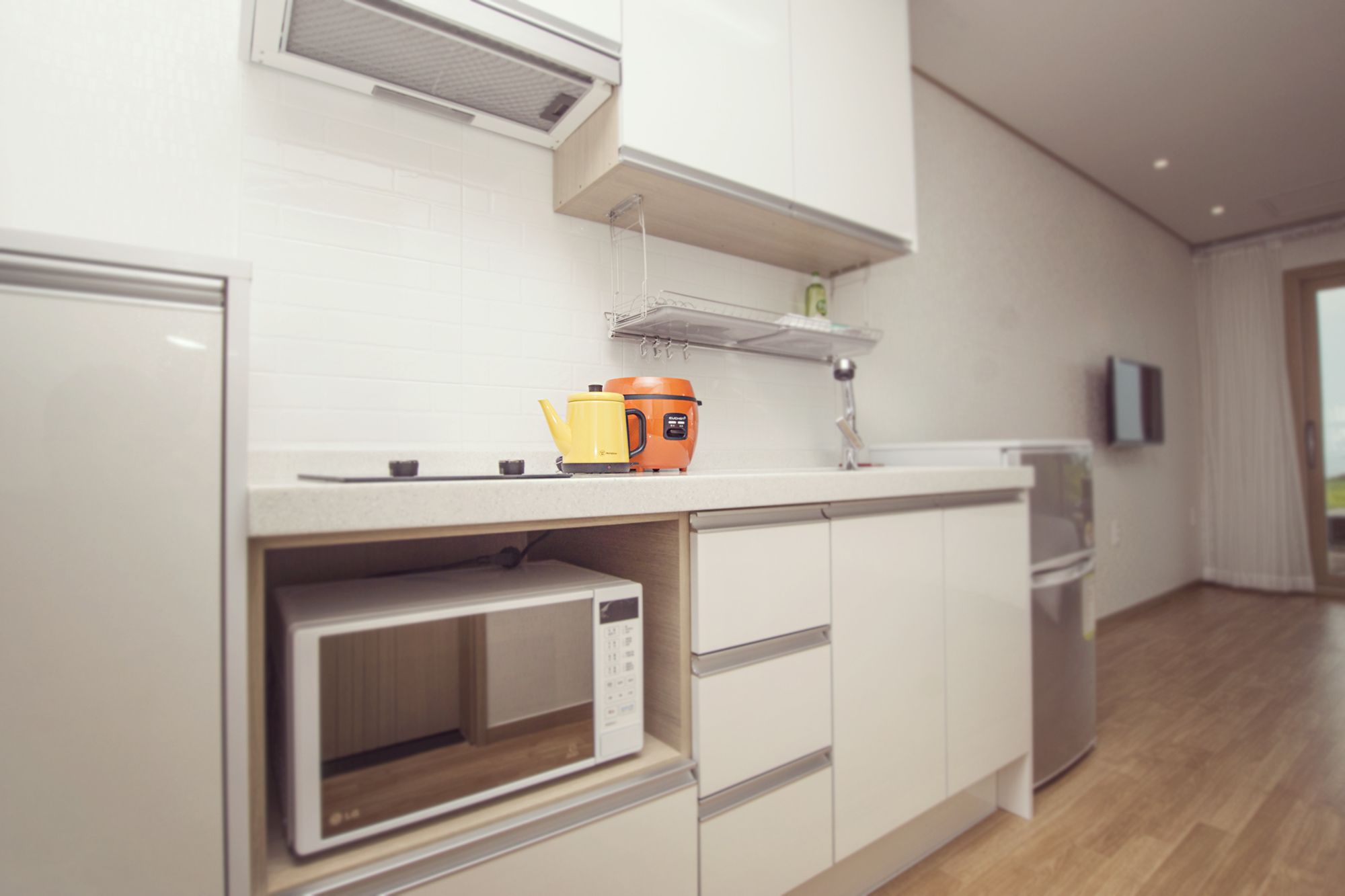 Cozinha moderna com armários brancos, micro-ondas embutido e cafeteira no balcão.