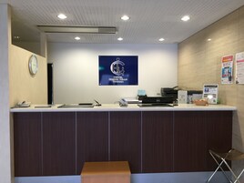 Bancada de recepção de hotel com relógio, visor digital e computador Dell.