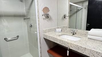 Casa de banho moderna com cabine de duche em vidro, lavatório com bancada de mármore e um espelho grande.